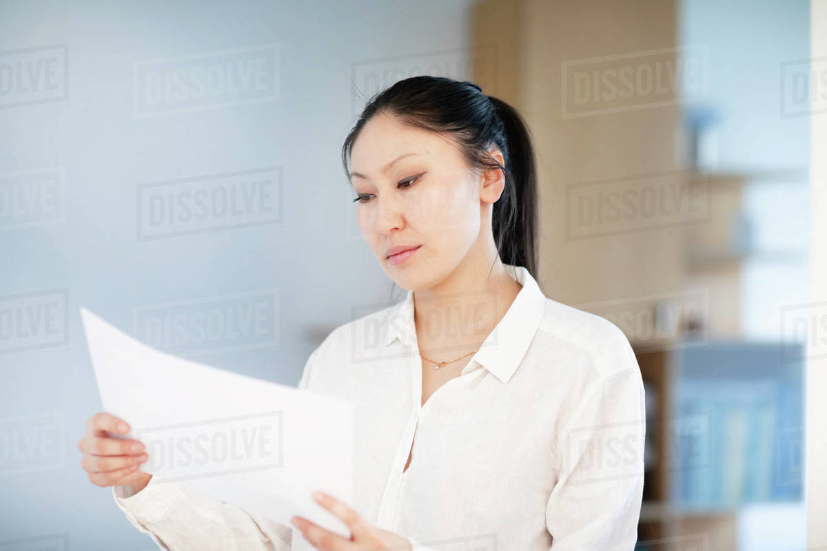 Serious businesswoman looking at documents in office - Royalty-free ...