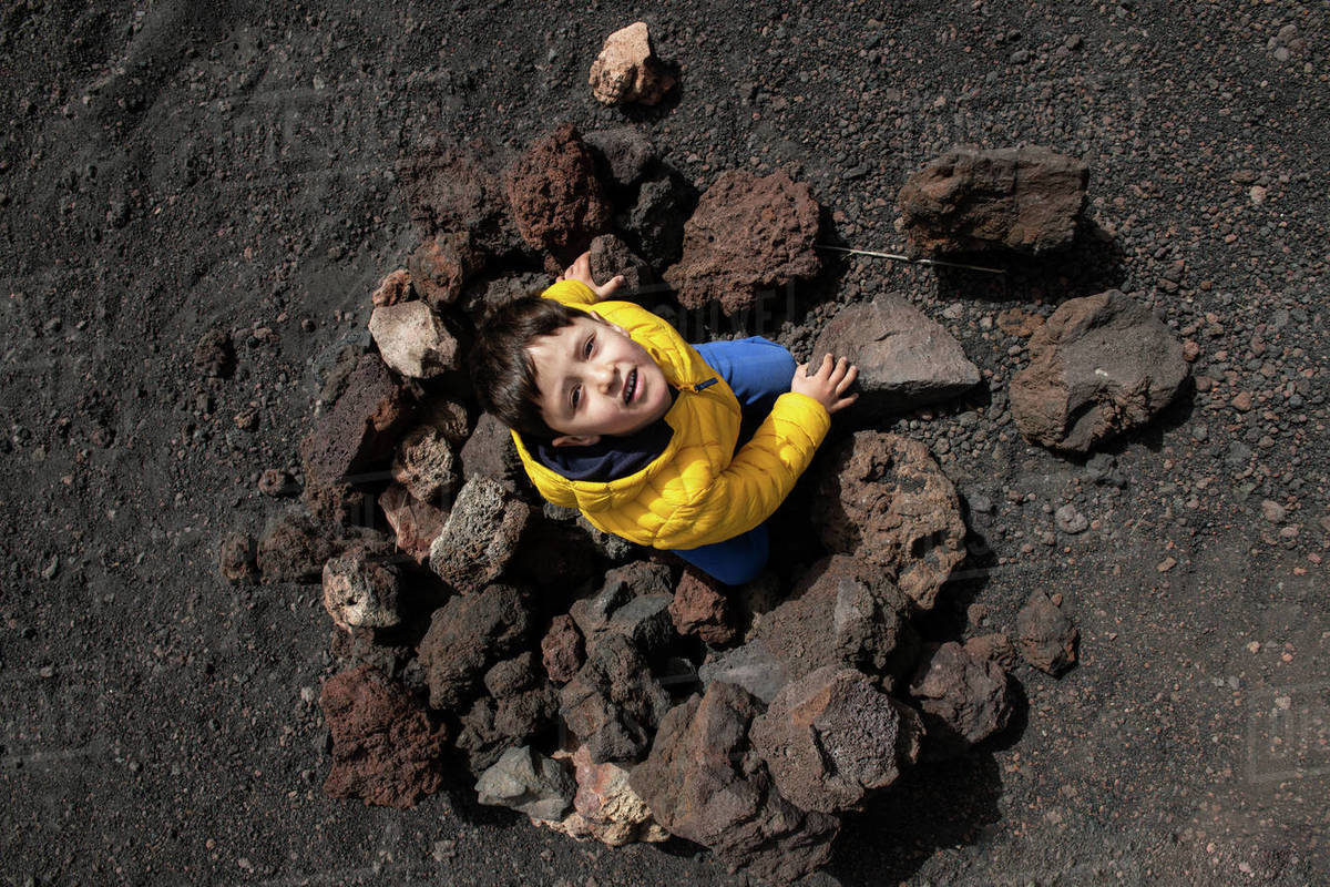 Italy, Sicily, Boy playing with rocks on Etna volcano - Royalty-free ...