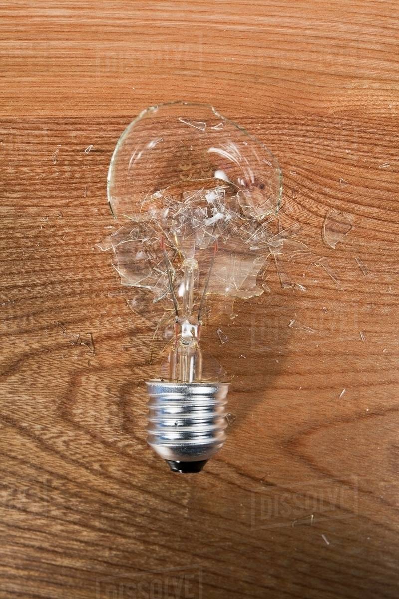 Smashed lightbulb against wooden background - Stock Photo - Dissolve