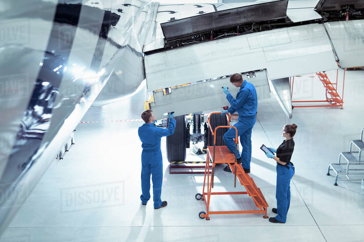 Team of apprentice aircraft maintenance engineers inspecting large ...