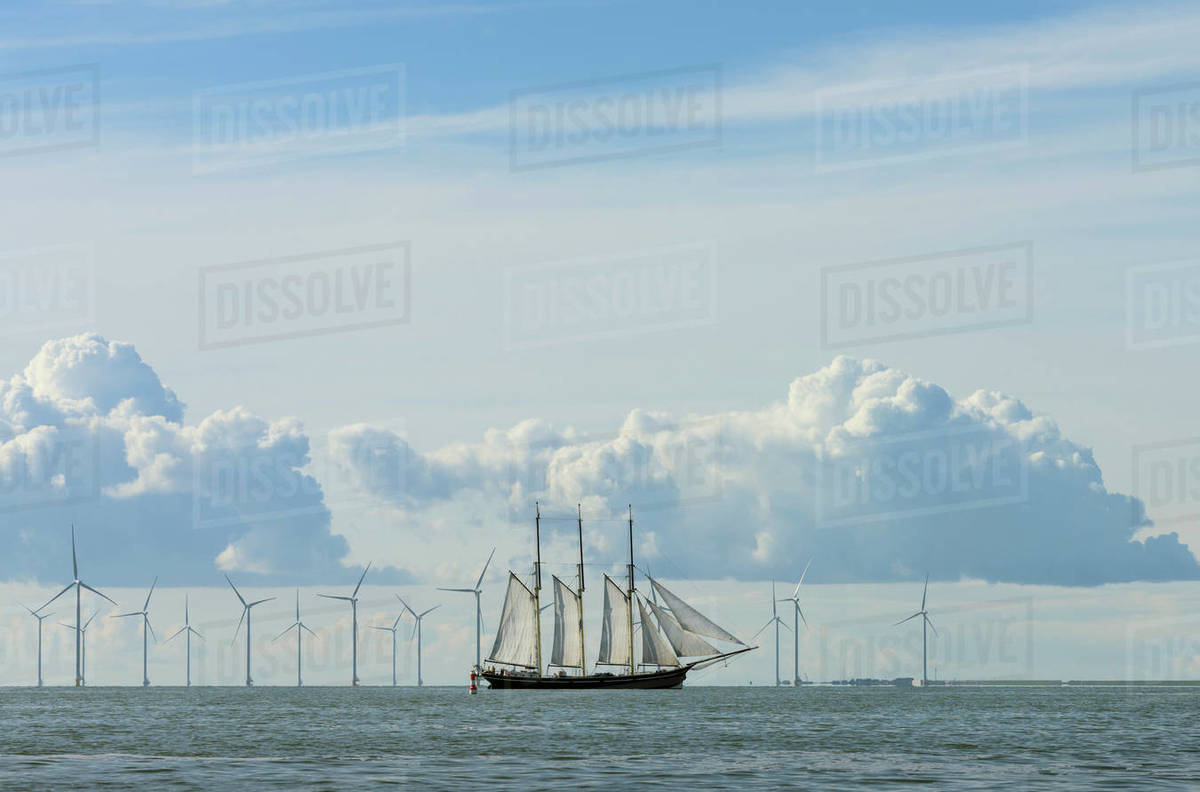 The Netherlands, Friesland, Historic sailing ship between wind turbines ...