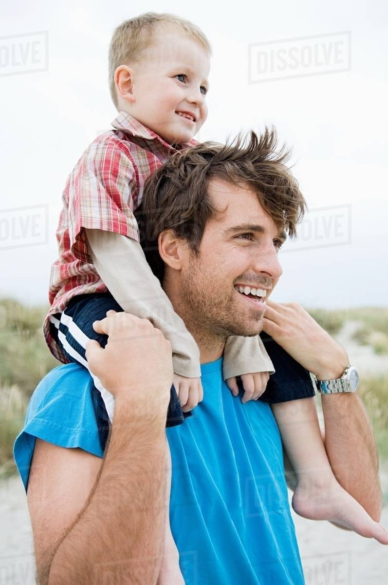 Young man carrying boy on shoulders - Royalty-free Stock Photo | Dissolve