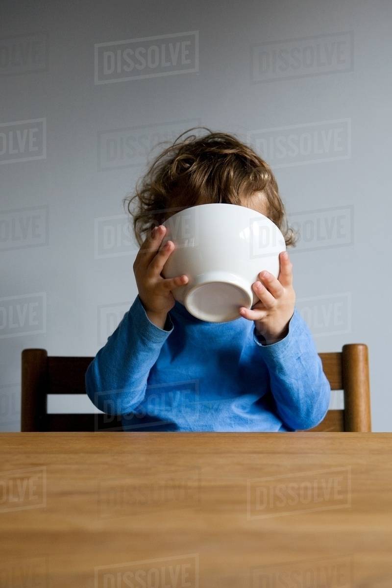 Little boy holding bowl to his face - Royalty-free Stock Photo | Dissolve