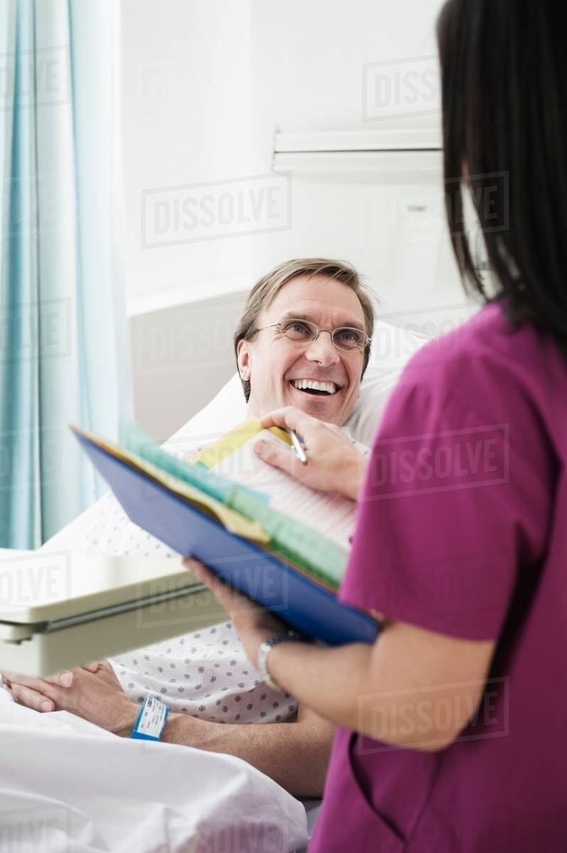 Nurse tending to smiling patient in hospital - Stock Photo - Dissolve