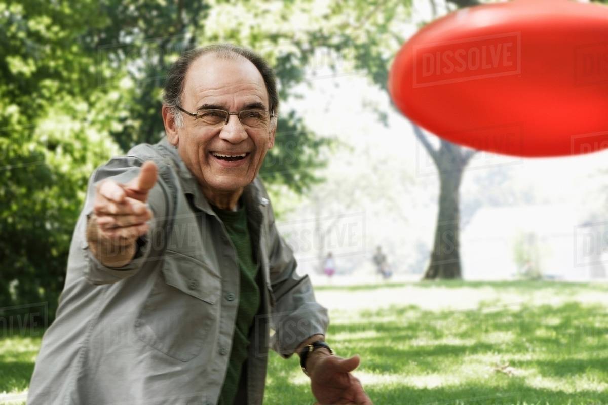 Senior man throwing red flying disc - Royalty-free Stock Photo | Dissolve
