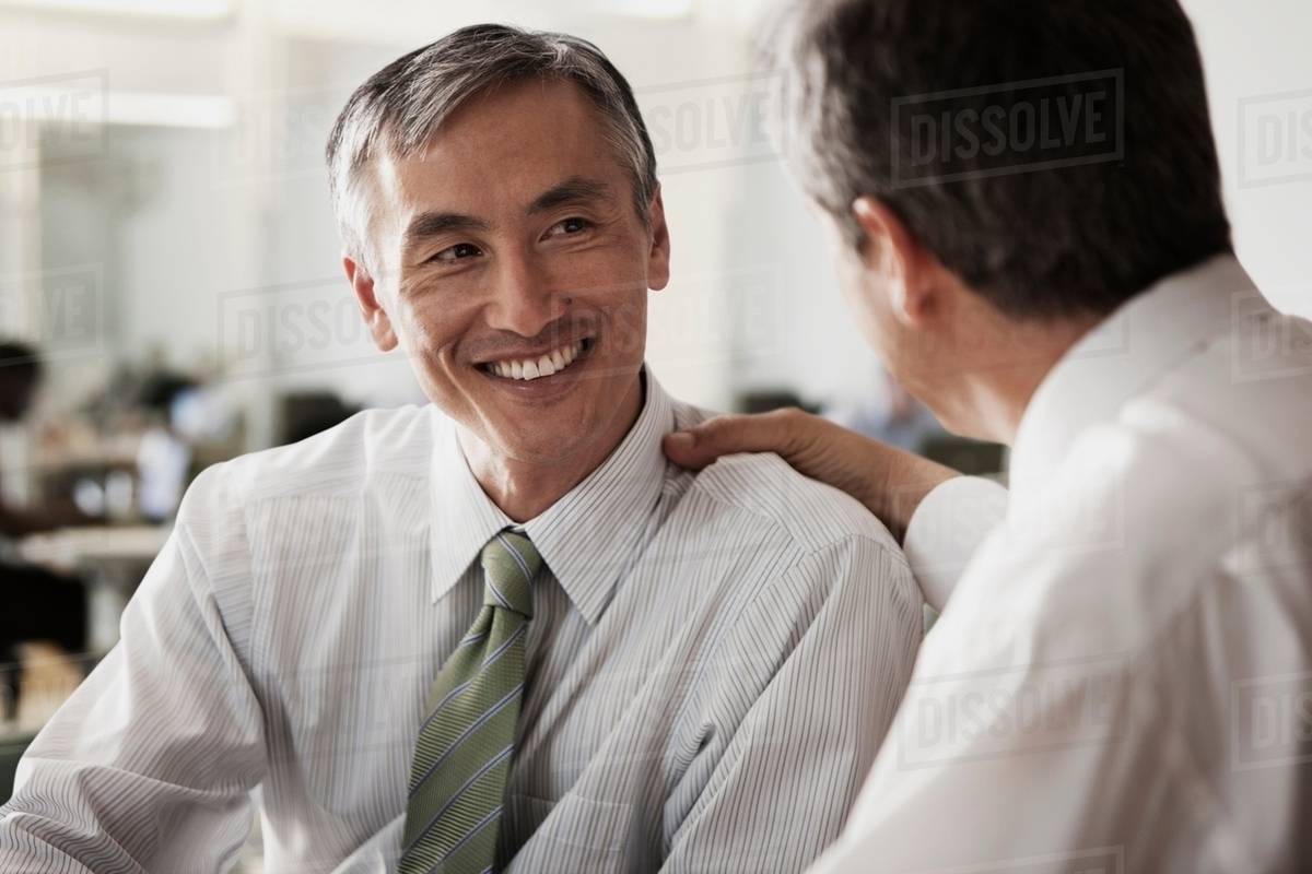 Businessman touching colleagues shoulder in office - Stock Photo - Dissolve