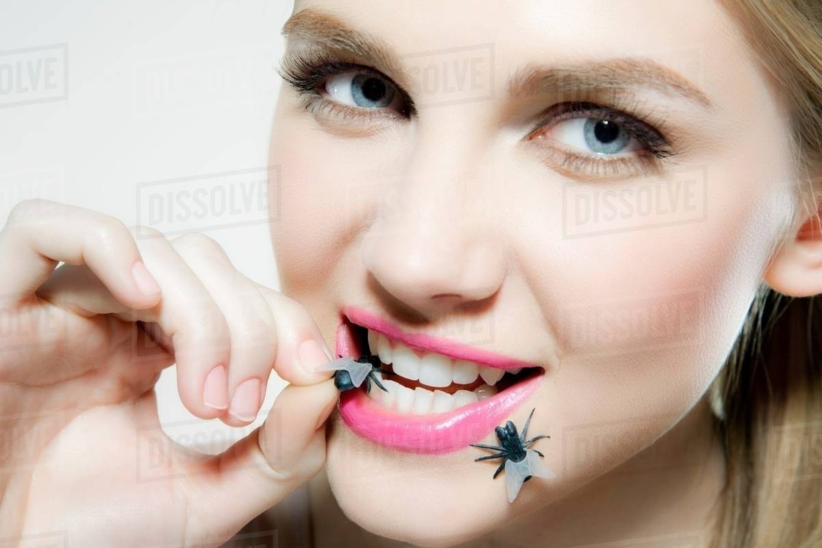 Young woman biting plastic fly - Stock Photo - Dissolve