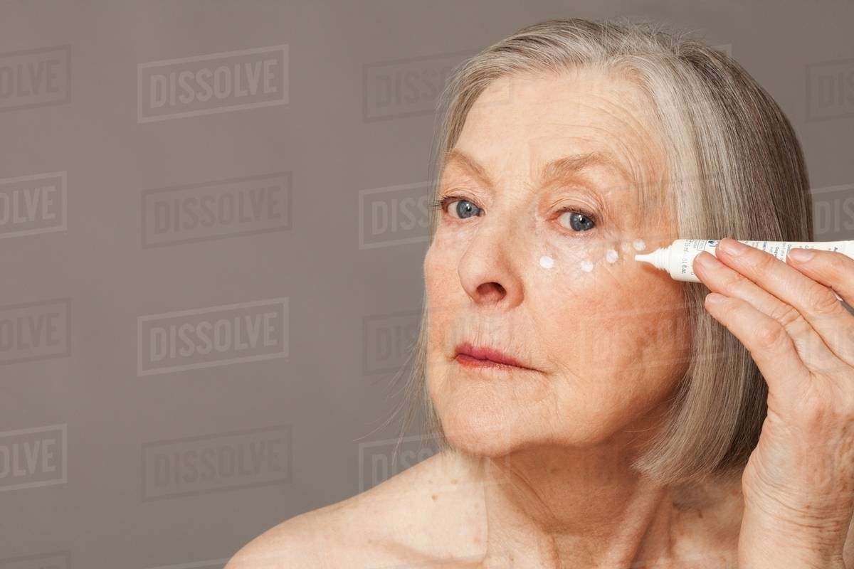 Senior woman applying eye cream - Royalty-free Stock Photo | Dissolve