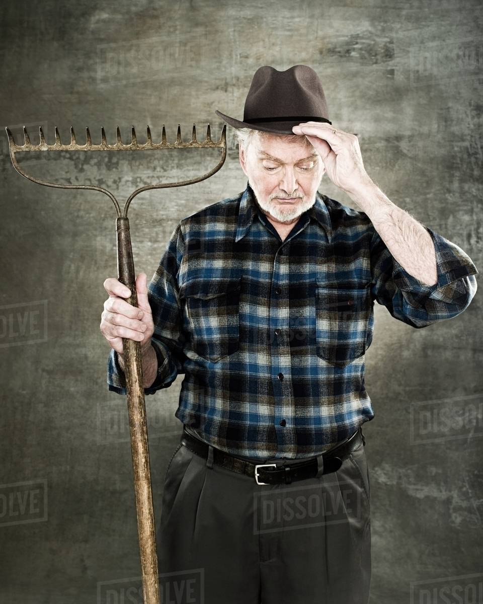 Portrait of a farmer holding a rake - Royalty-free Stock Photo | Dissolve