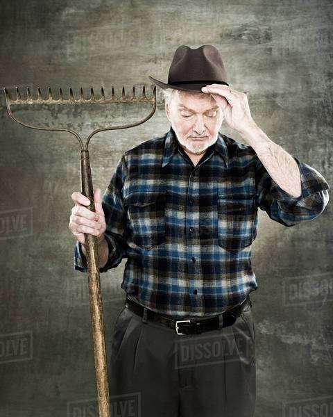 Portrait of a farmer holding a rake - Royalty-free Stock Photo | Dissolve