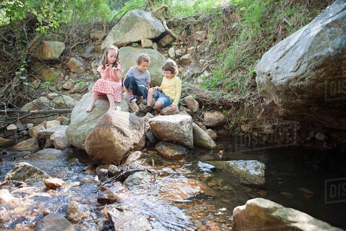Children on rocks by river - Stock Photo - Dissolve
