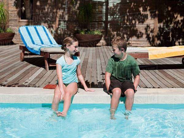 Boy and girl on edge of swimming pool - Stock Photo - Dissolve
