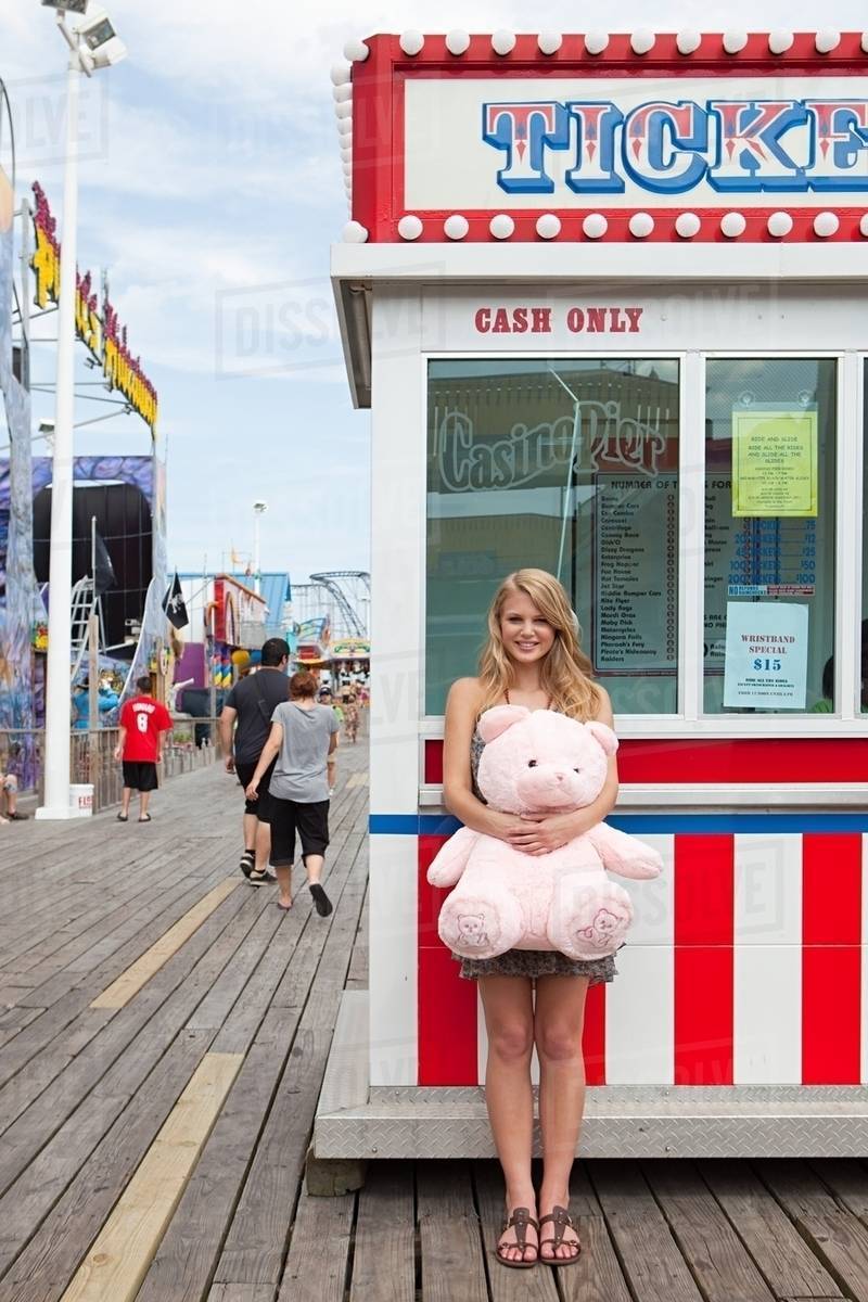 Teenage girl by ticket booth with teddy bear - Stock Photo - Dissolve