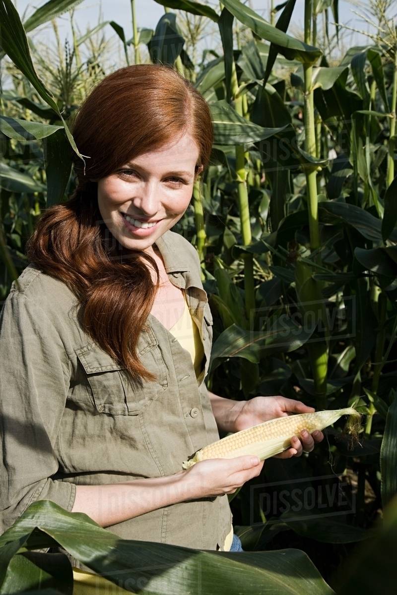 Young woman holding corn cob - Royalty-free Stock Photo | Dissolve
