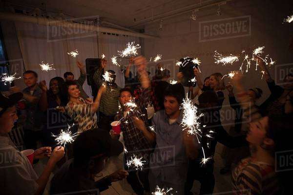 People dancing at party with sparklers - Stock Photo - Dissolve