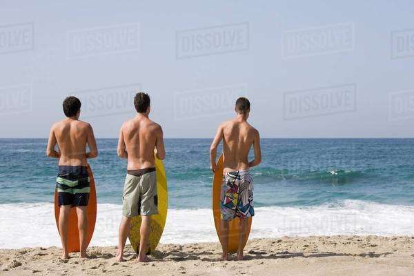 Three young men on beach with surfboards - Royalty-free Stock Photo ...