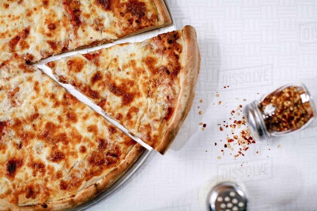 Pizza slice with spilled chili flakes - Stock Photo - Dissolve
