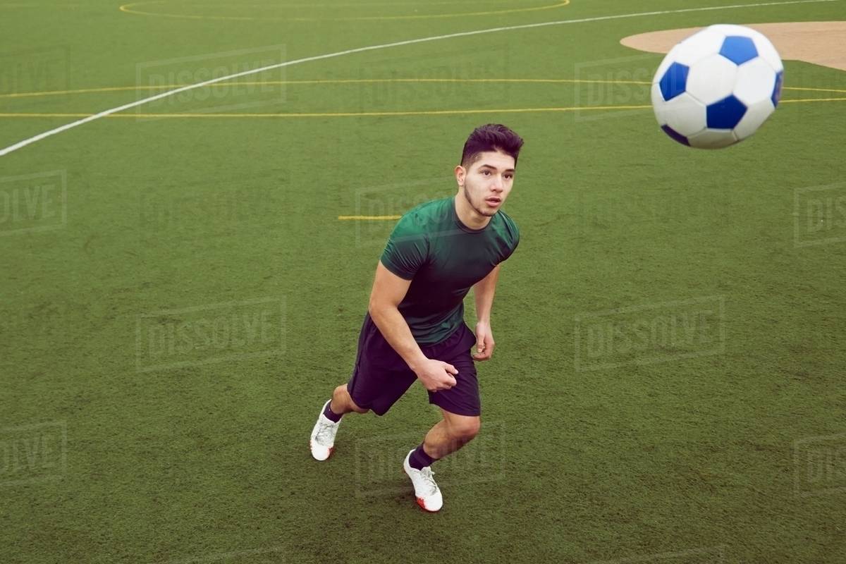 Young man playing soccer on football pitch - Stock Photo - Dissolve