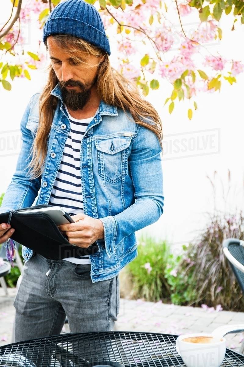 Mid adult man putting laptop in case - Stock Photo - Dissolve