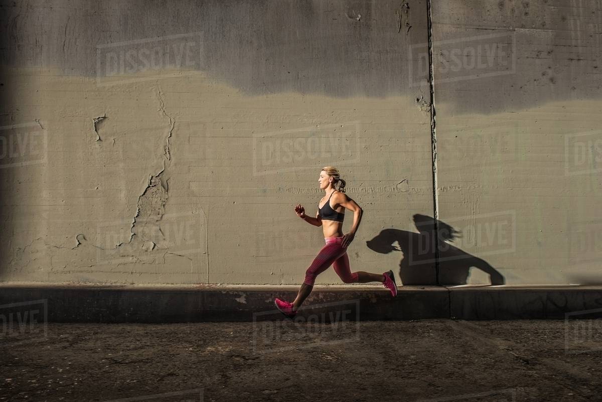 Female runner running on sidewalk - Stock Photo - Dissolve