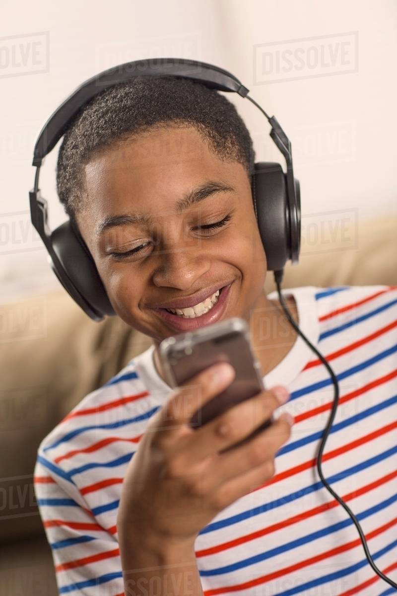 Teenage boy wearing headphones reading smartphone texts - Royalty-free ...