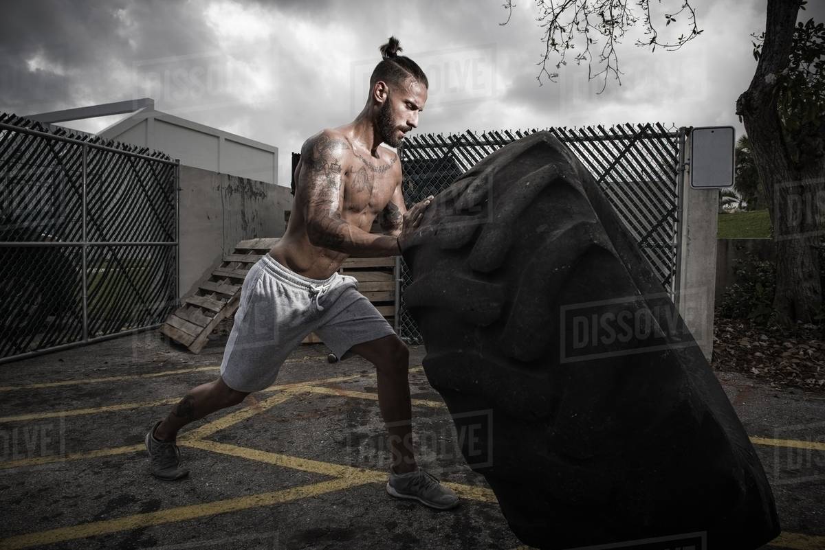 Male boxer training with truck tyre in yard - Stock Photo - Dissolve