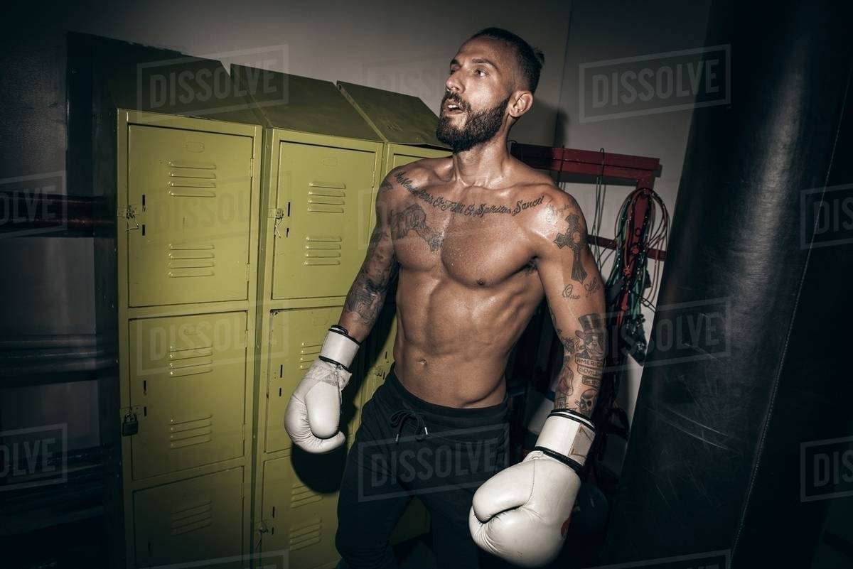 Tattooed male boxer poised wearing boxing gloves in gym - Stock Photo ...
