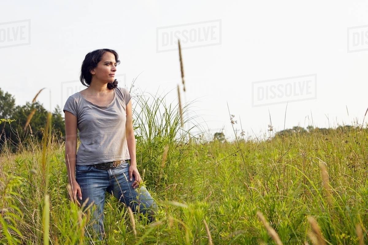 Woman looking out from field of long grass - Royalty-free Stock Photo ...