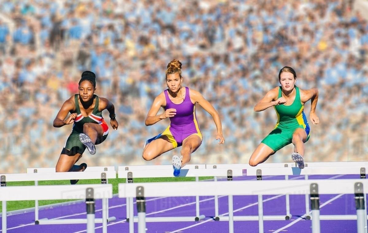 Runners jumping over hurdle on track - Royalty-free Stock Photo | Dissolve