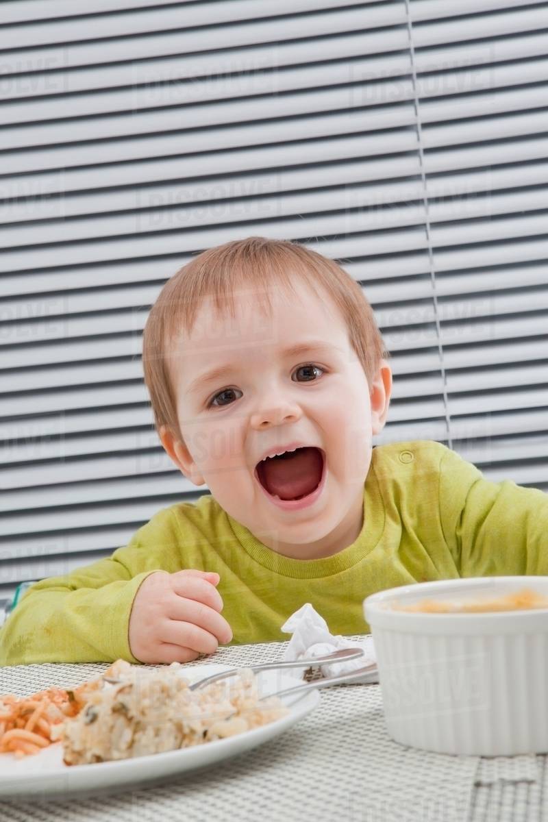 Baby boy feeding himself at dining table - Royalty-free Stock Photo ...