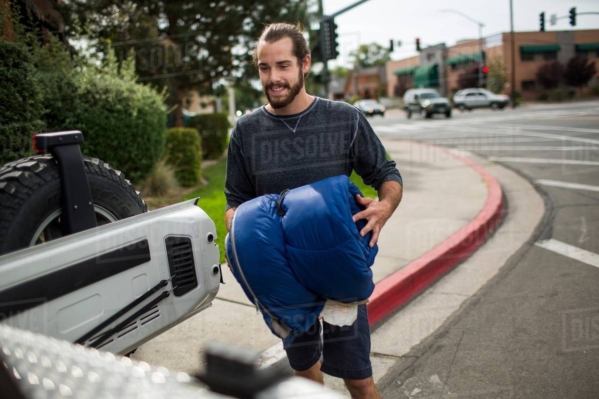 Young man loading jeep for road trip - Royalty-free Stock Photo | Dissolve