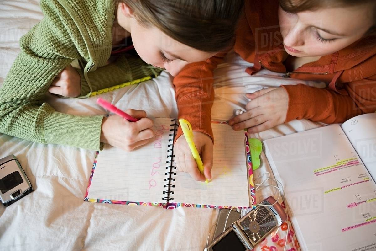 Two teenage girls writing in a book - Royalty-free Stock Photo | Dissolve