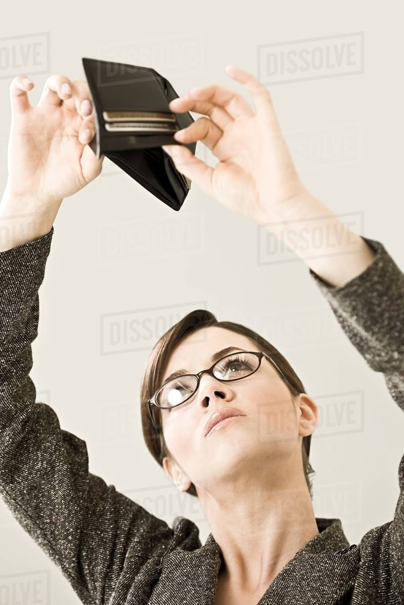 A young woman looking in an empty wallet - Stock Photo - Dissolve