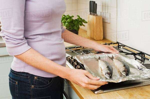 Woman cooking fish - Stock Photo - Dissolve