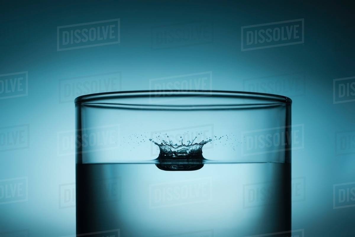 Drop splashing in glass of water - Stock Photo - Dissolve