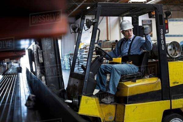 Worker using forklift in metal plant - Stock Photo - Dissolve