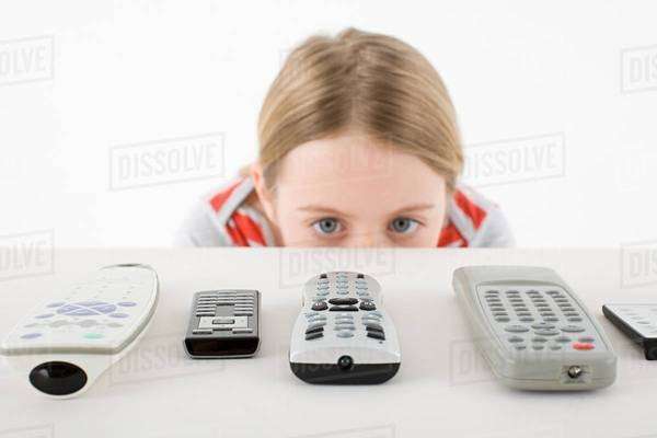 Girl looking at remote controls - Royalty-free Stock Photo | Dissolve