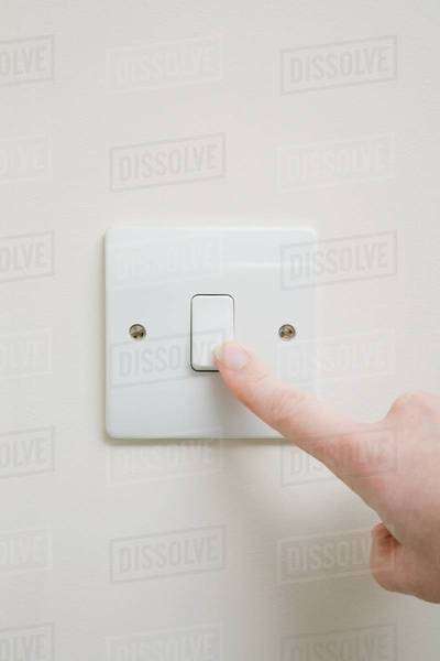 Person using light switch - Stock Photo - Dissolve