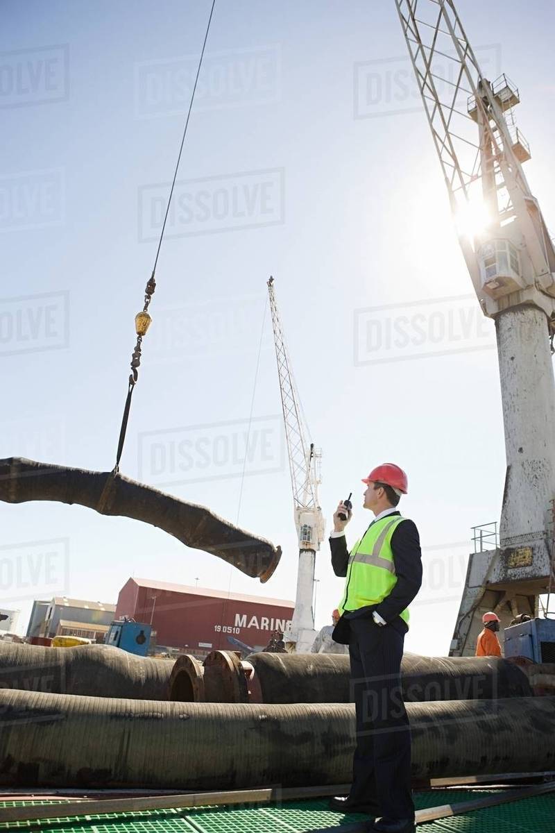 Engineer and crane lifting pipes - Royalty-free Stock Photo | Dissolve