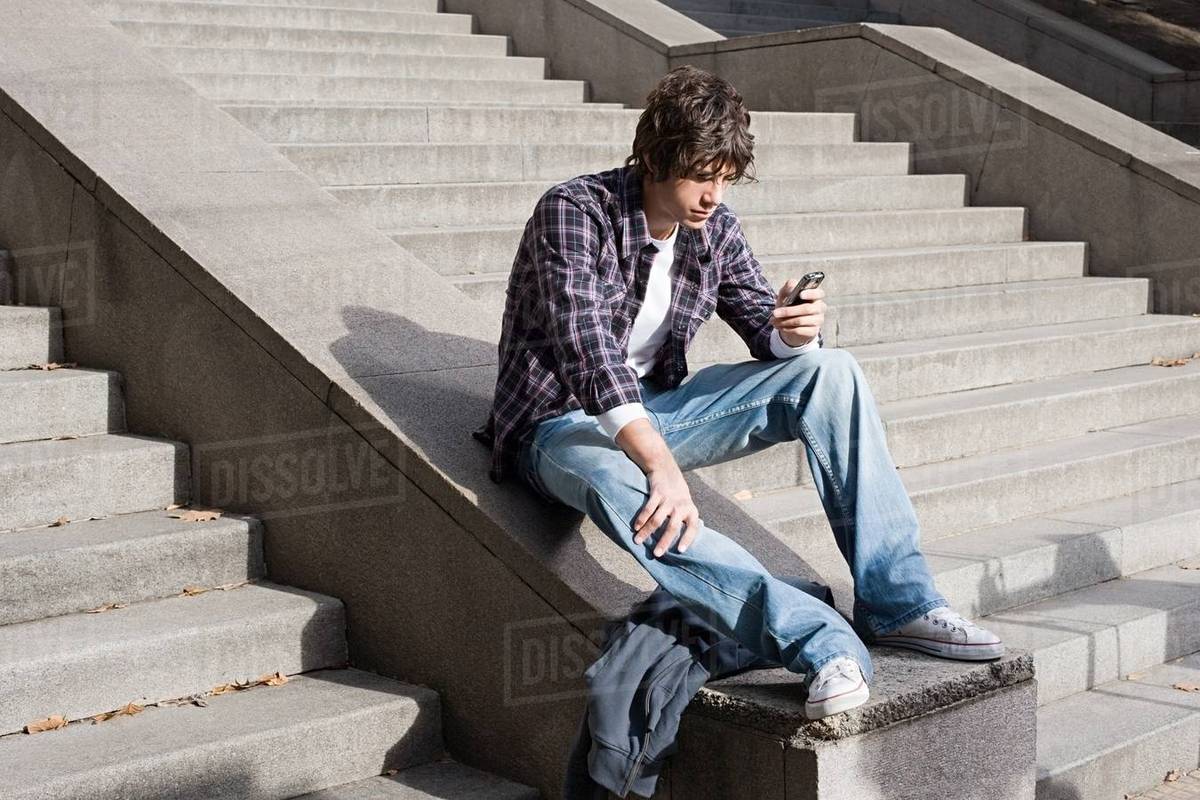 Boy text messaging on stairway - Stock Photo - Dissolve