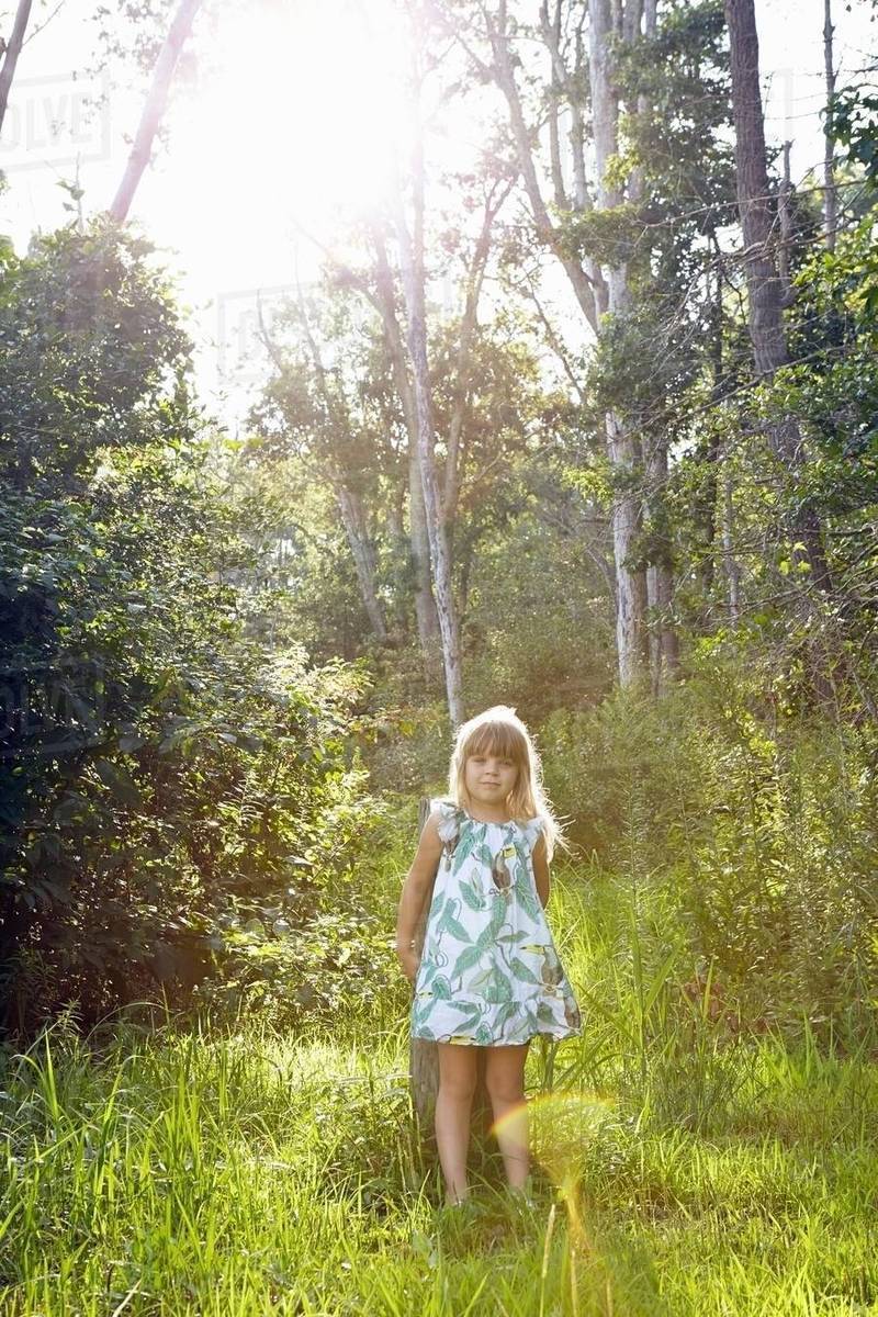 Girl standing against tree in forest - Royalty-free Stock Photo | Dissolve