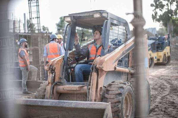 Construction worker driving excavator on construction site - Stock ...
