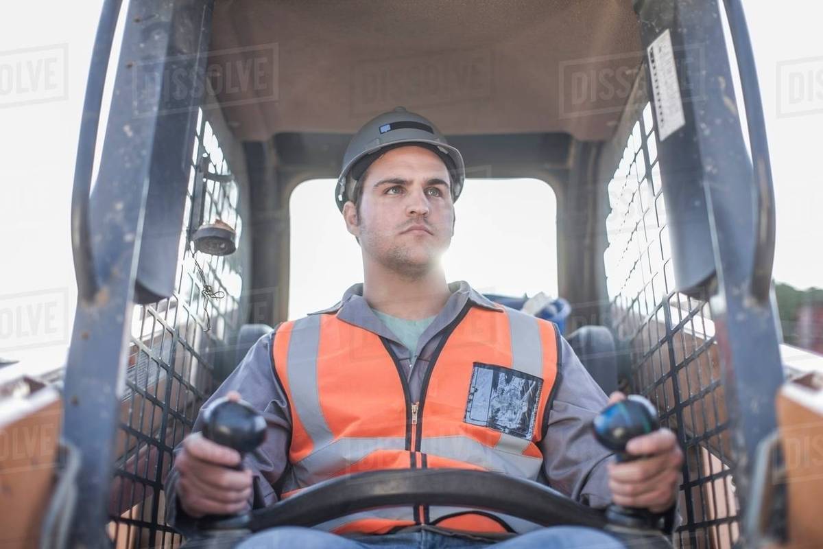 Young man driving excavator on construction site - Royalty-free Stock ...