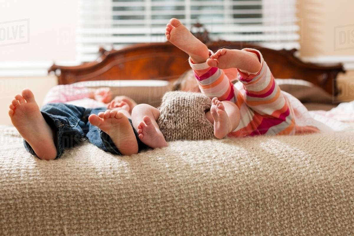 Children laying with infant on bed - Royalty-free Stock Photo | Dissolve