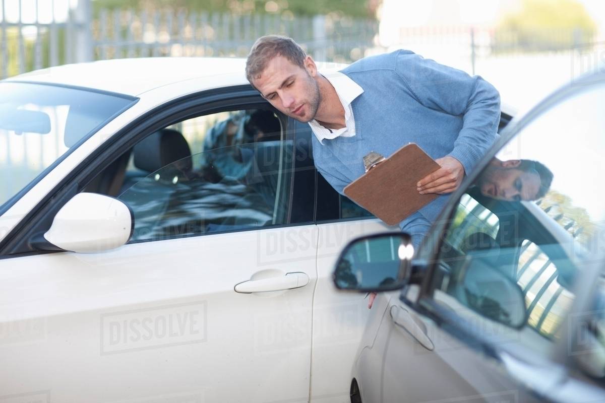 Man assessing damage on car after car accident - Stock Photo - Dissolve