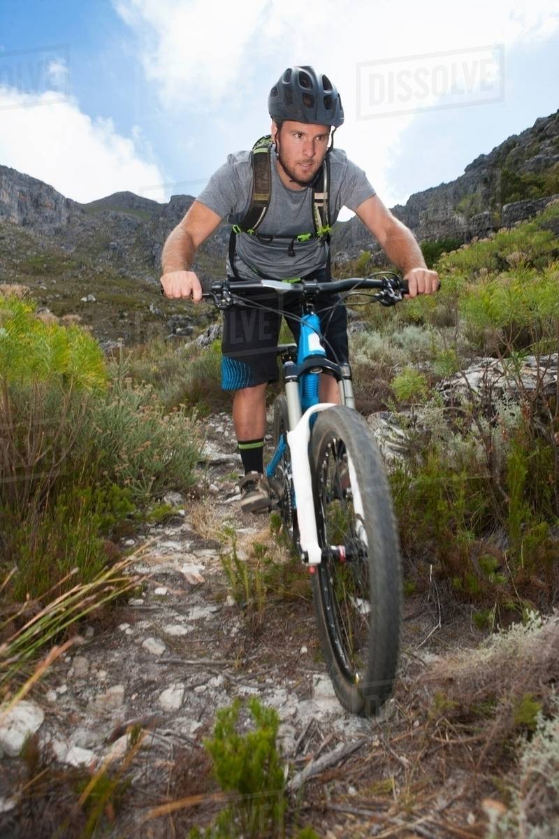 Young man mountain biking through mountains - Stock Photo - Dissolve