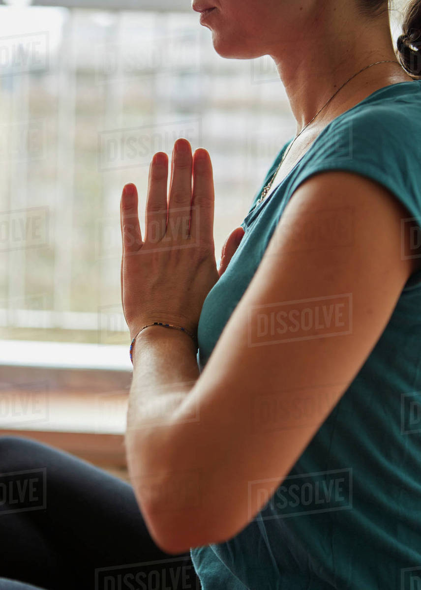 Cropped side view of woman hands together meditating - Royalty-free ...