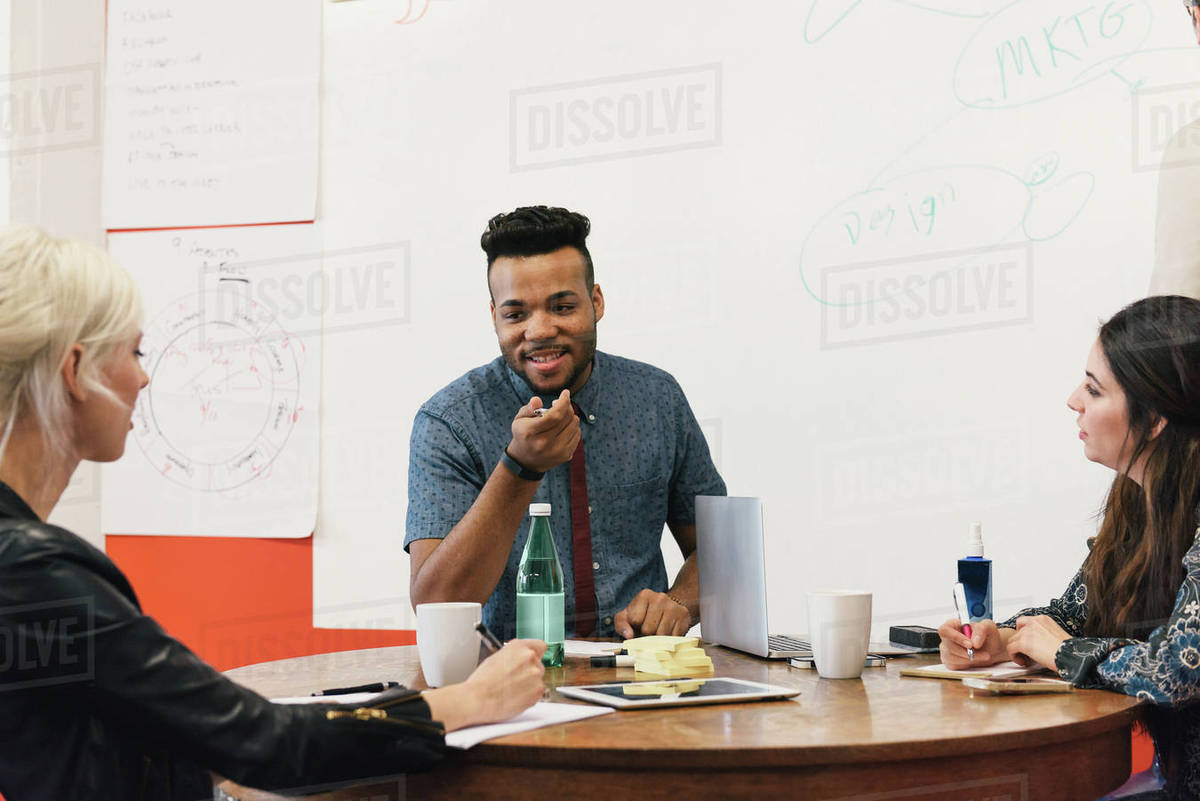 Colleagues in office sitting at table chatting - Royalty-free Stock ...