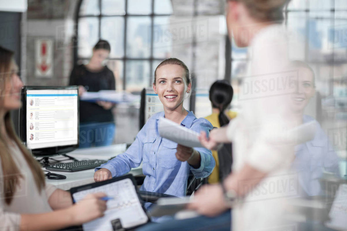 Female manager handing out paperwork in office - Stock Photo - Dissolve