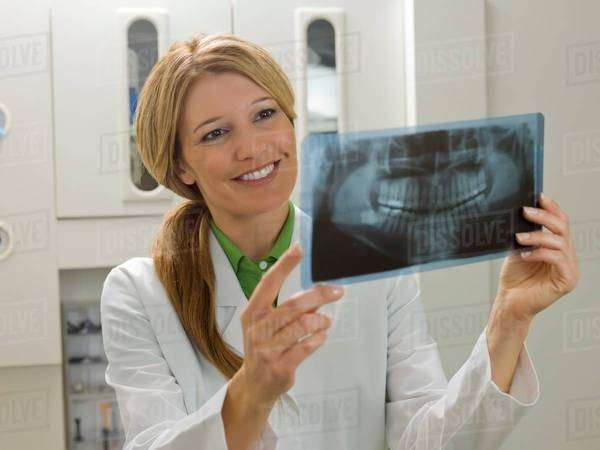 Dentist looking at x-ray, smiling - Royalty-free Stock Photo | Dissolve